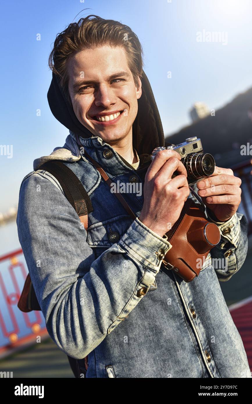 Stylish man photographing on retro camera. Tourist stay on the bridge ...