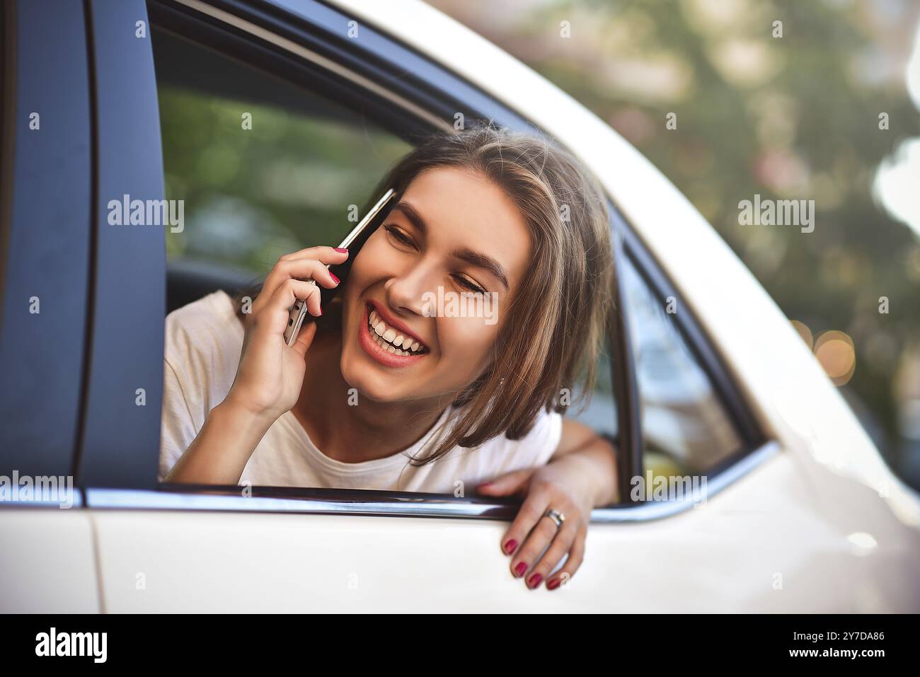 Beautiful woman with phone smiling while sitting on the back seat in ...