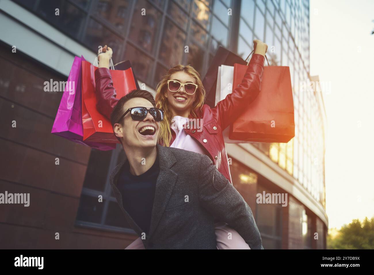 Happy couple shopping together and having fun. Boyfriend carrying his ...