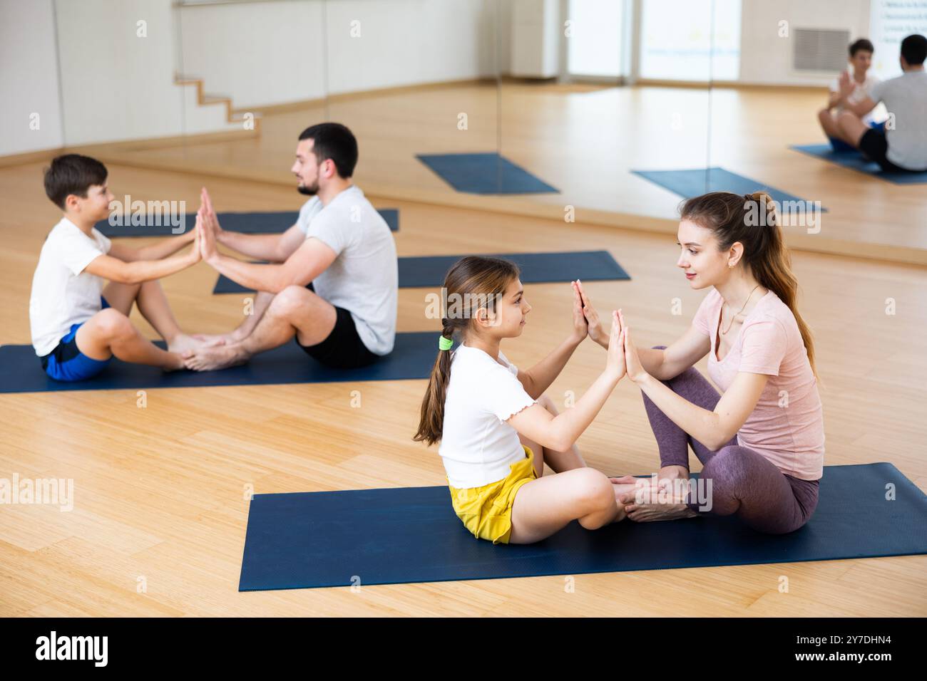 Teen girl practicing partner yoga in pair with mother during family ...