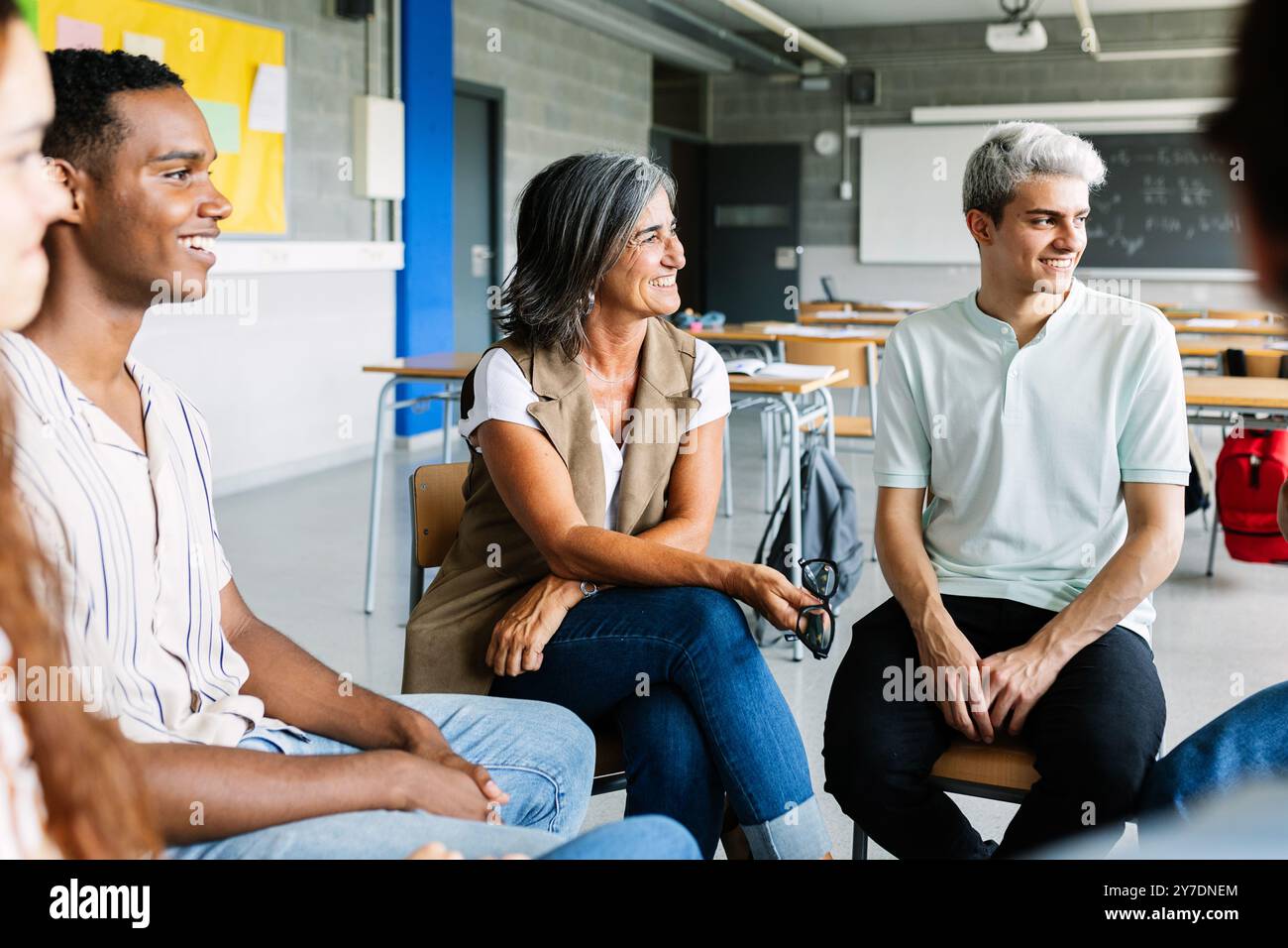 Young high school students talking with teacher in focus group therapy ...