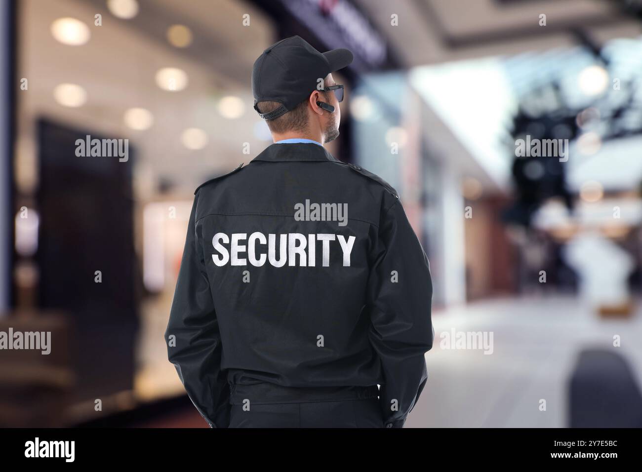 Security guard in uniform and earpiece in shopping mall, back view ...