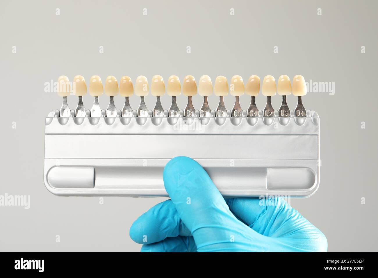 Doctor with teeth color chart on gray background, closeup. Dental ...