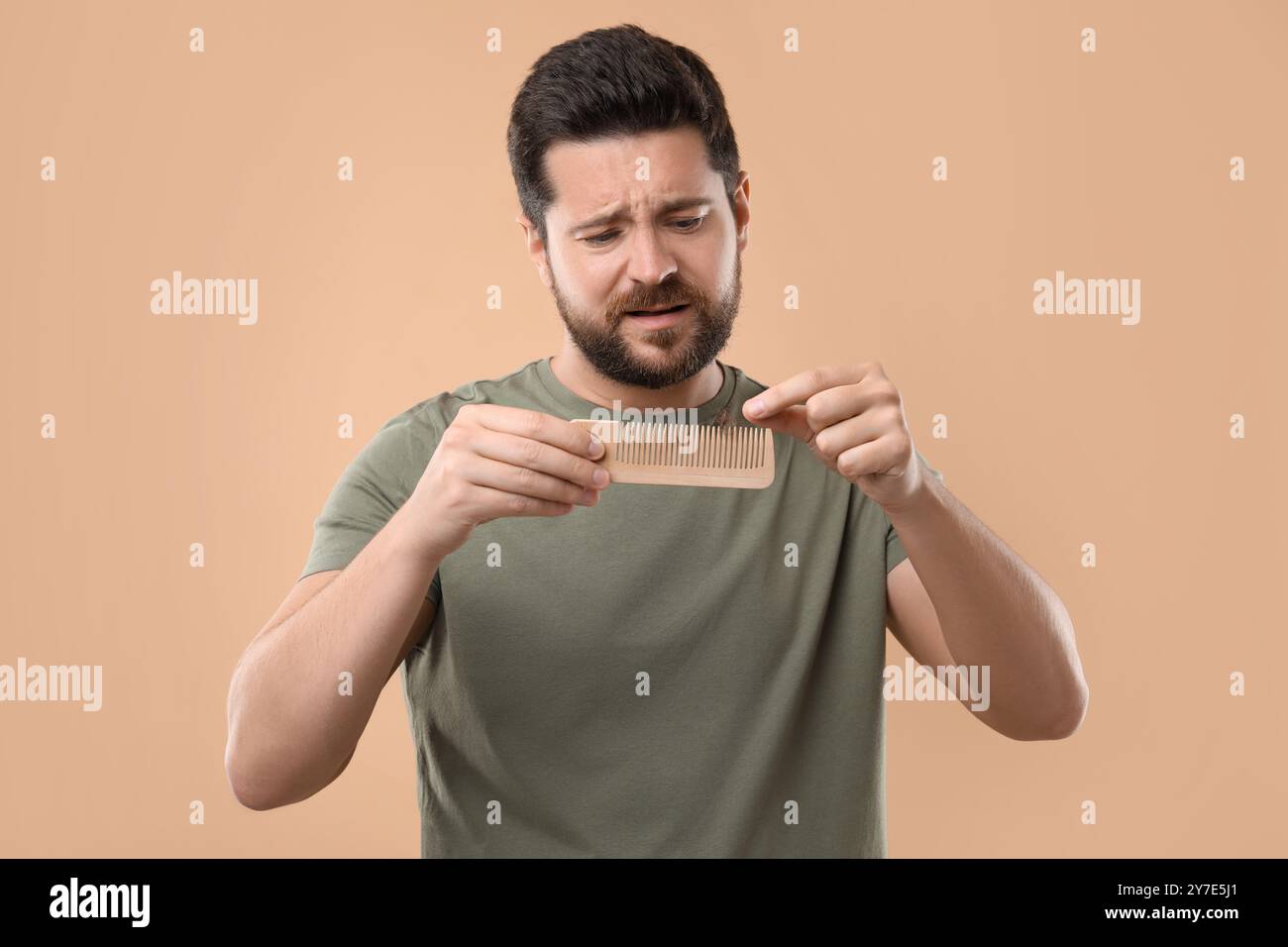 Sad man taking his lost hair from comb on beige background. Alopecia ...