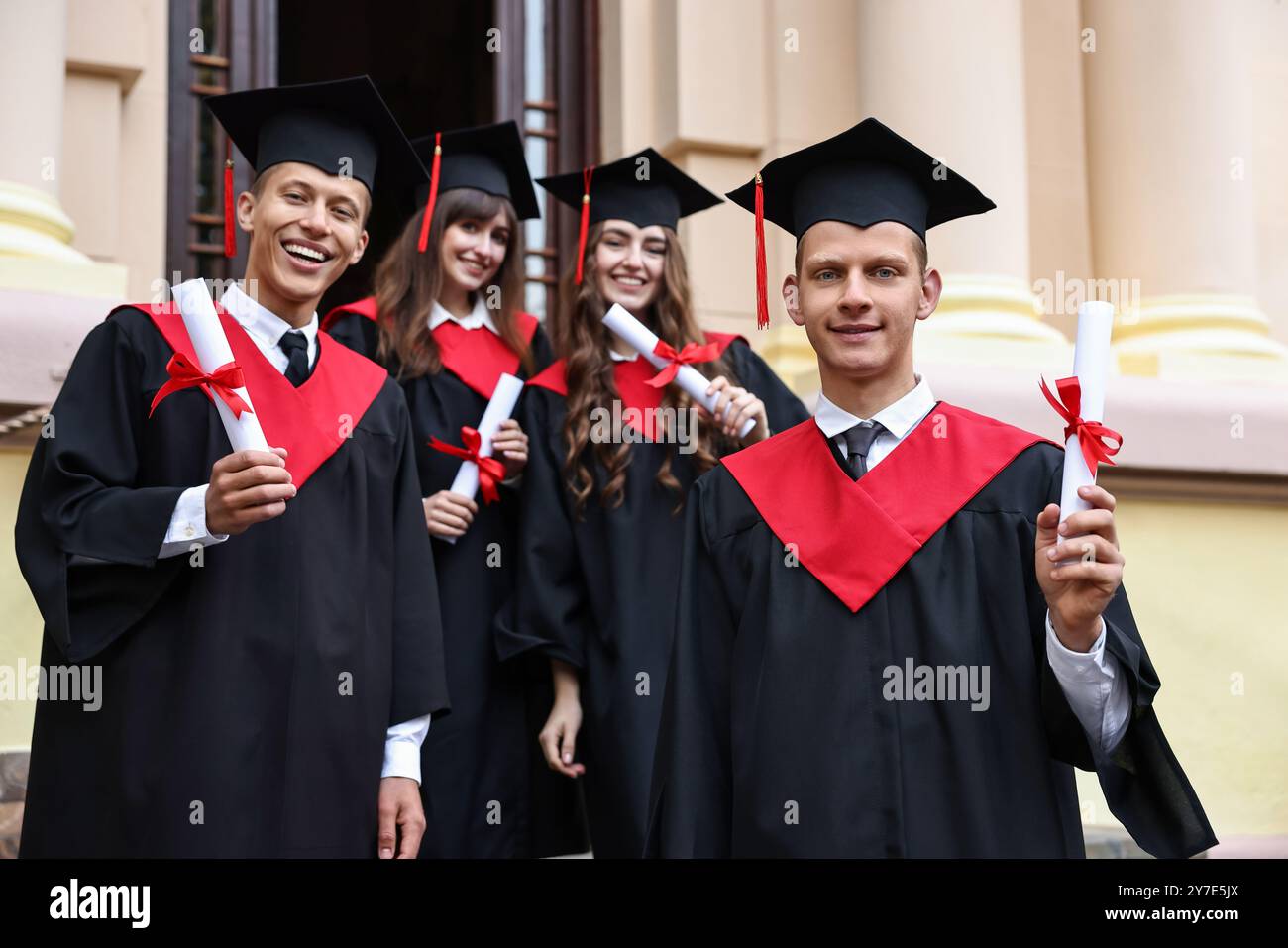 Graduation ceremony. Happy students with diplomas outdoors, selective ...