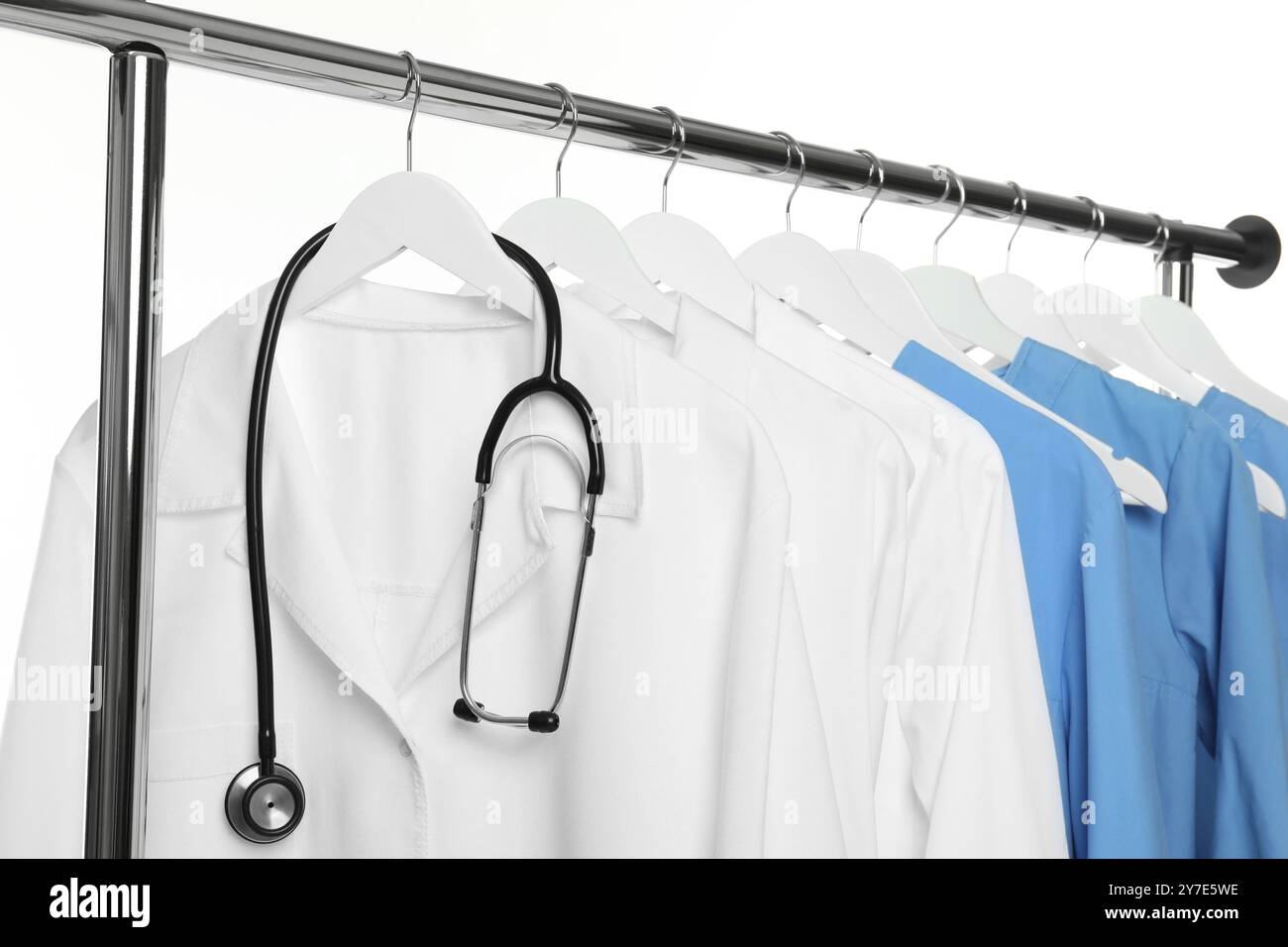 Different medical workers' uniforms and stethoscope on clothing rack ...