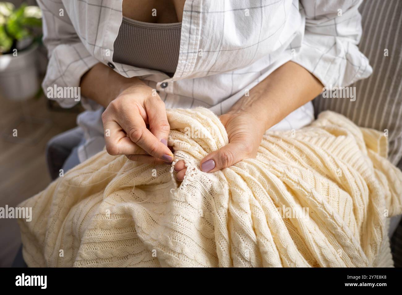 Clothes repair concept. A woman uses her hands to sew up a hole in a ...
