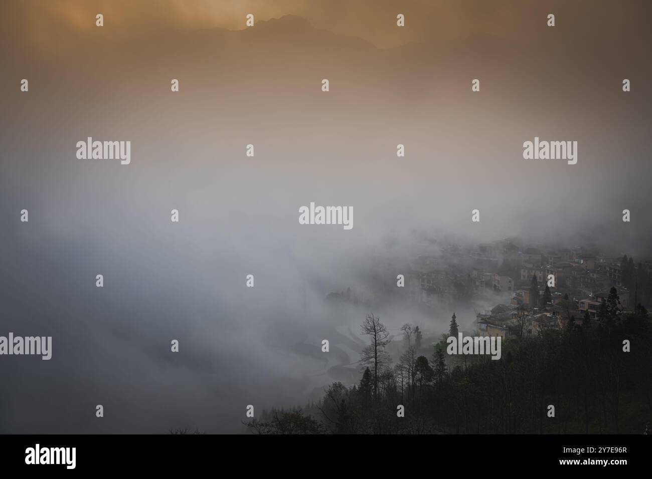 Orange sunrise sky at the rice terraces, dense fog and Duoyishu village ...