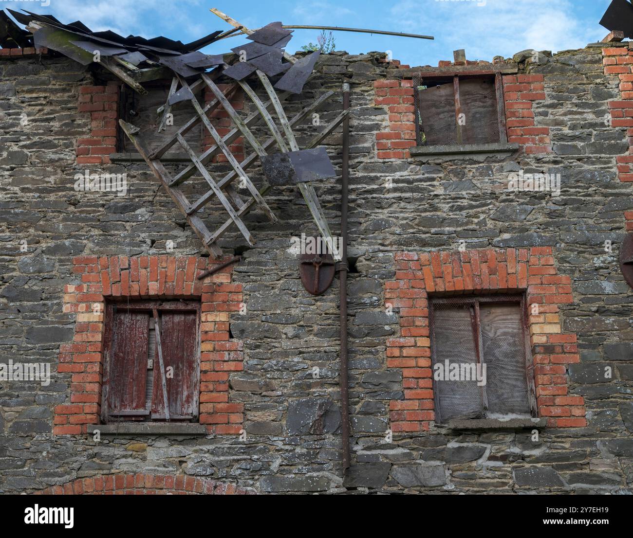 The wall of an abandoned, industrial building shows crumbling stone and ...