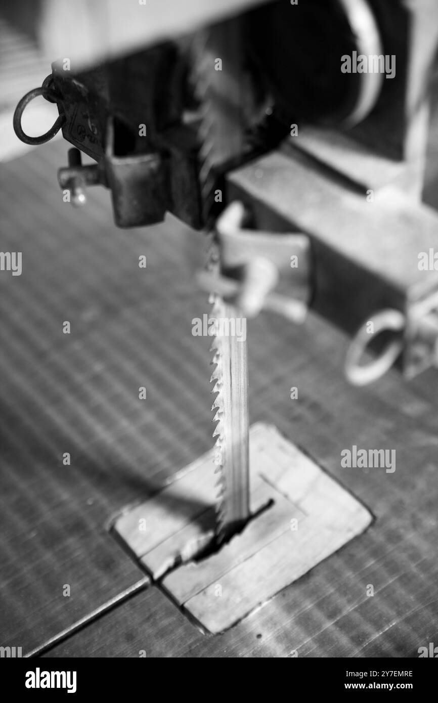 Vertical bandsaw blade is cutting through wood in a workshop, with ...