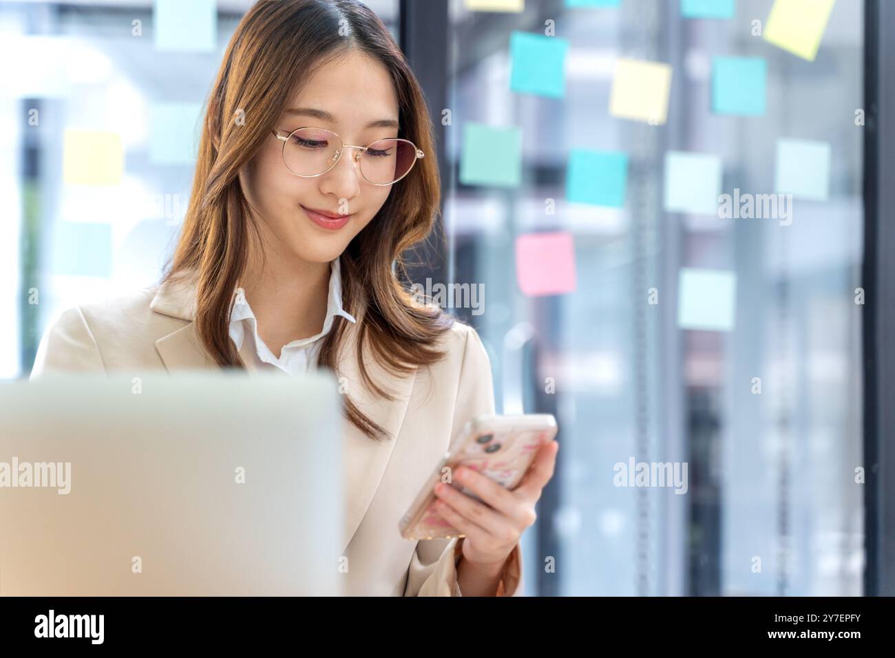 Happy young business woman working on her project at the office and checking her messages on her ...
