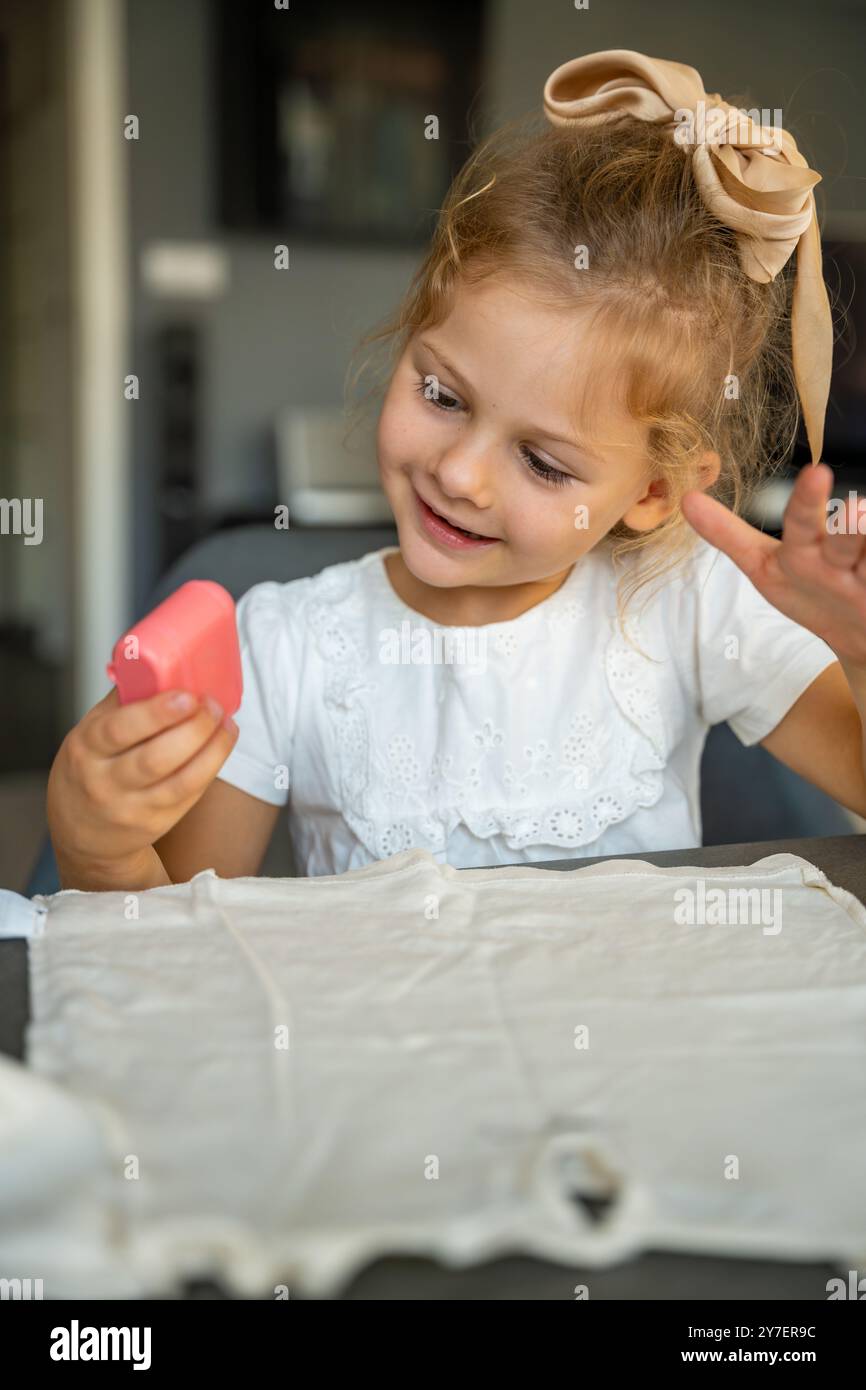 Little girl with a stamp with a name for signing children's things ...