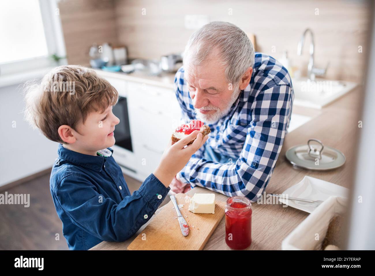 Boy and grandpa making breakfast in the kitchen. Grandfather spending ...