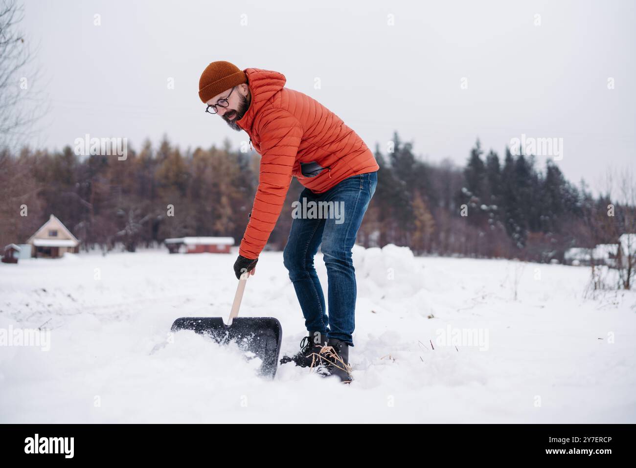 Man shoveling snow with shovel, cleaning driveway in front of the house ...