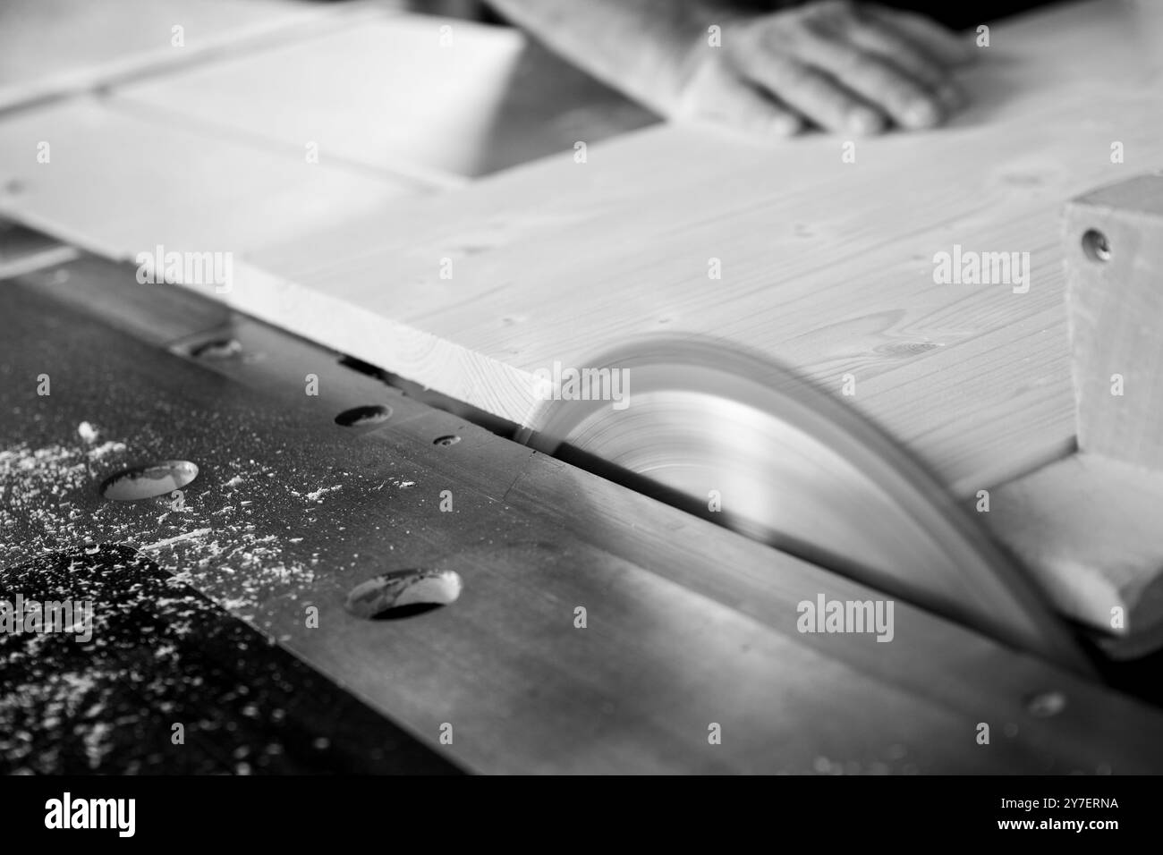 Skilled carpenter cutting wooden plank with circular saw in cozy ...