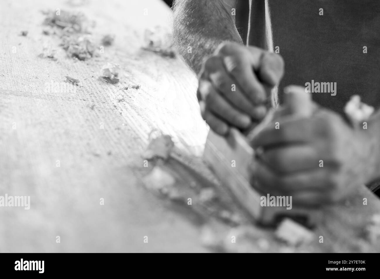 Close up of carpenter's hands using a hand plane for smoothing a plank ...