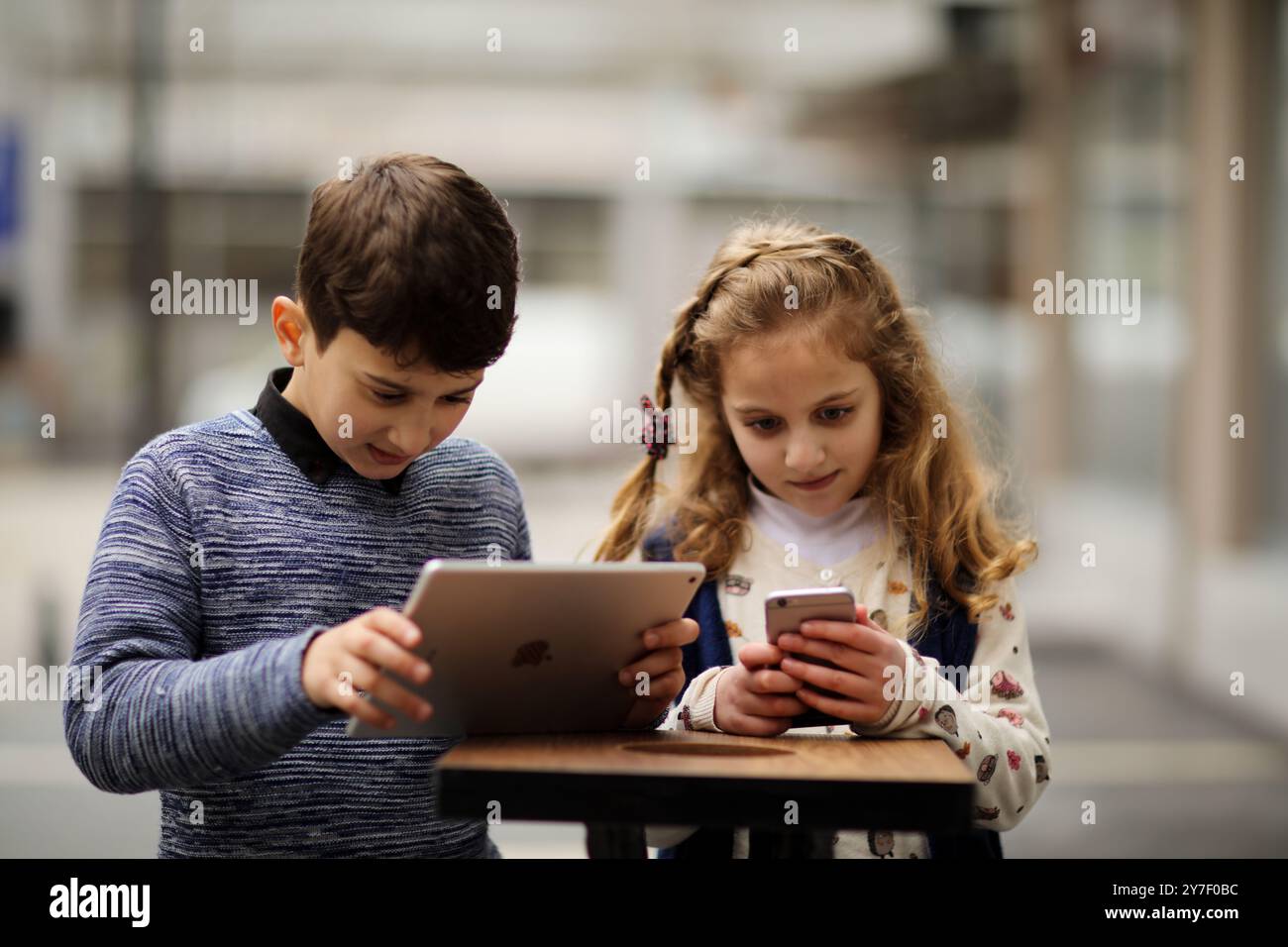 Children play with their smartphones and ipad in their home without ...
