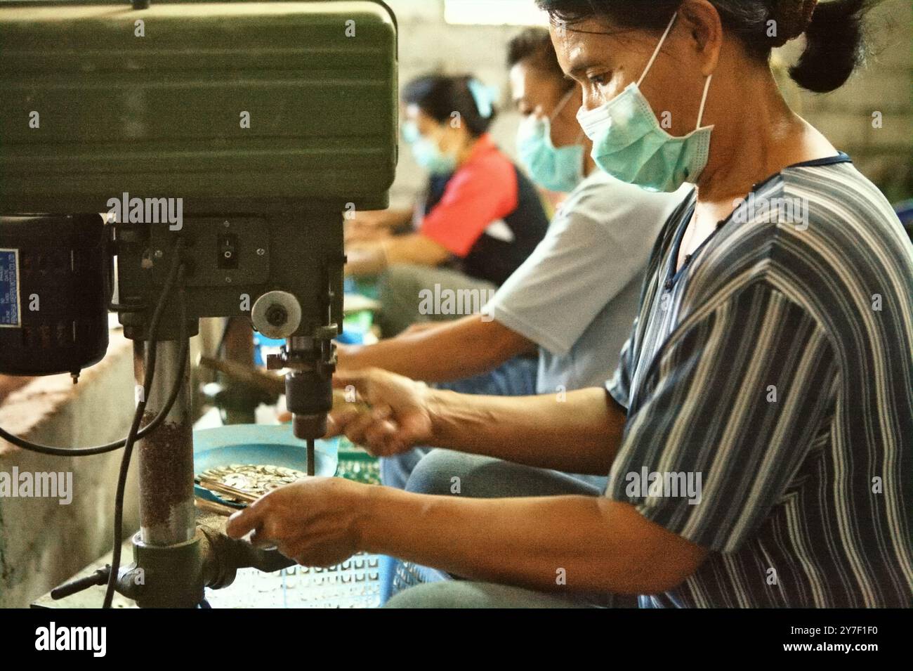 Women working at a factory producing traditional coins with hollow ...