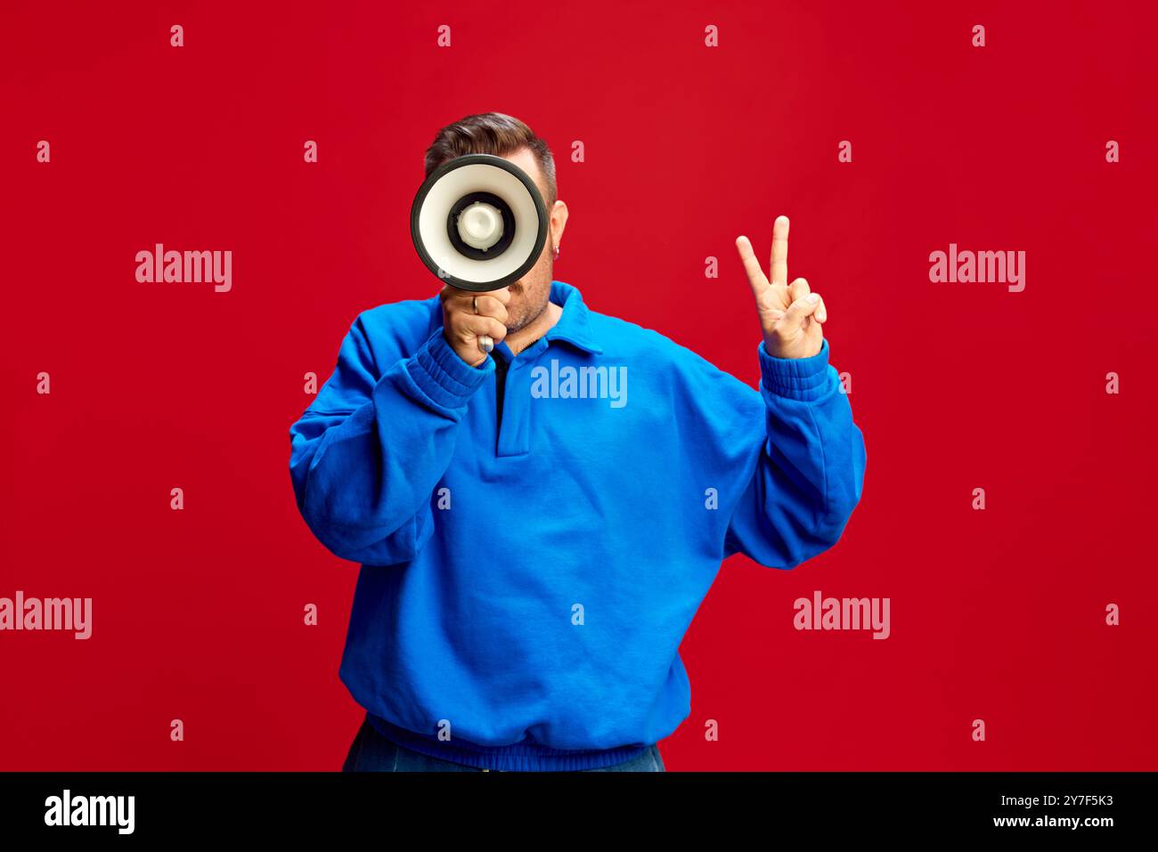 Person flashes peace sign while speaking through megaphone, symbolizing ...