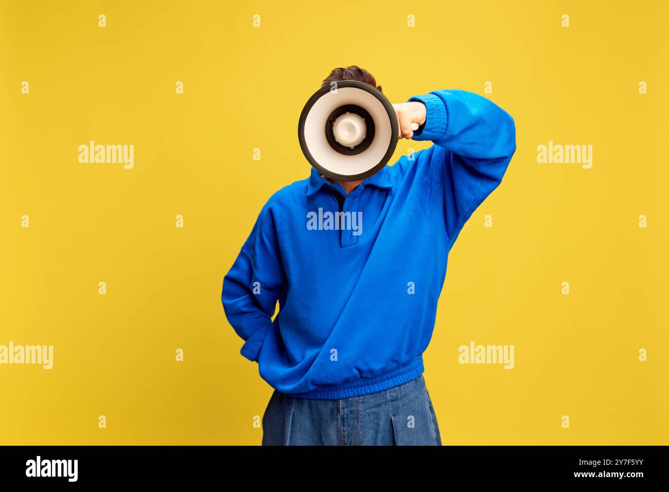 Person holds megaphone close to face and rests their hand on hip in ...