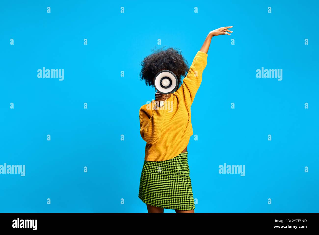 Woman shouting to megaphone, pointing to sky, inspiring confidence ...