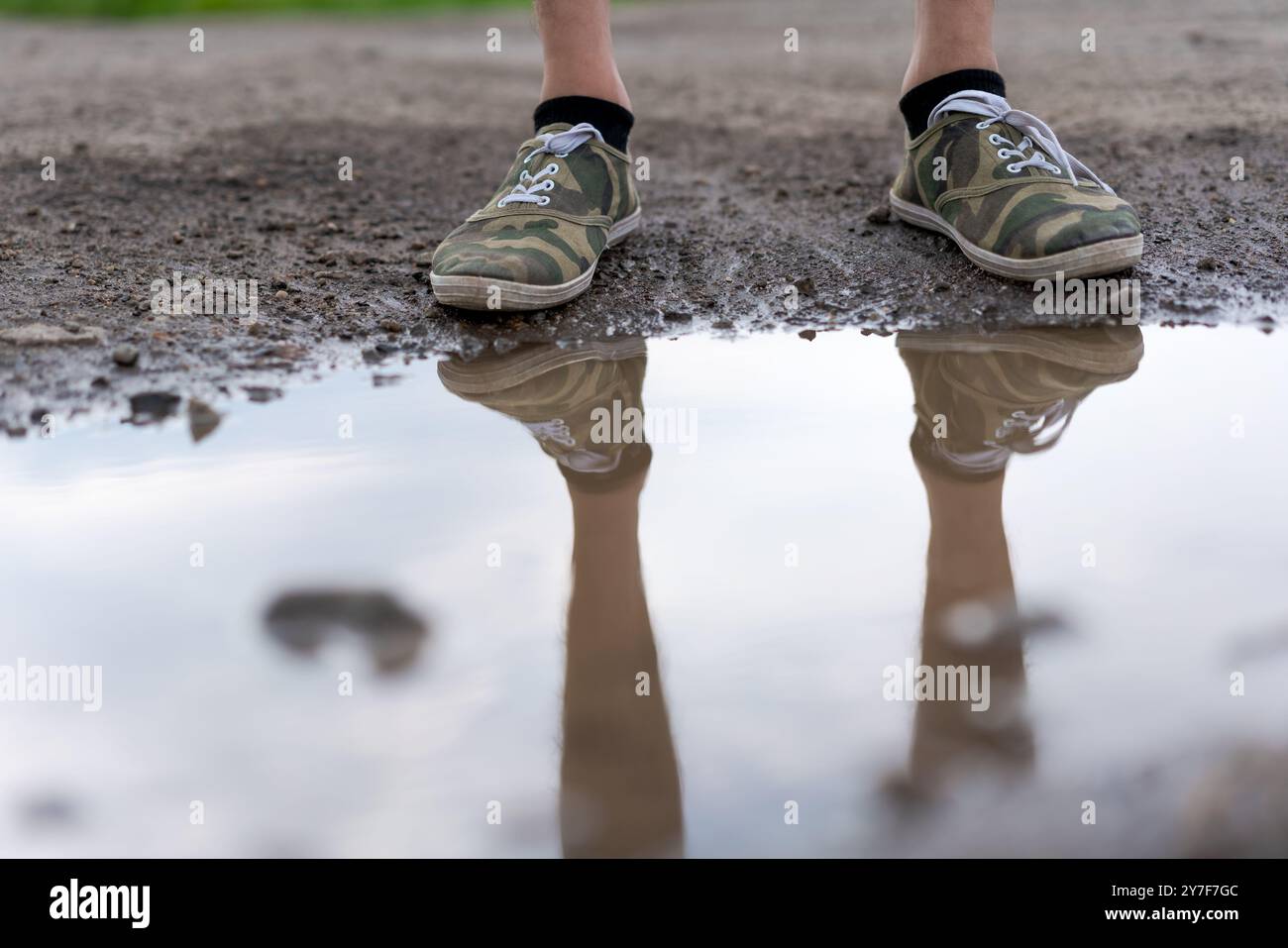 A person is standing in a puddle of water with their feet in the water ...