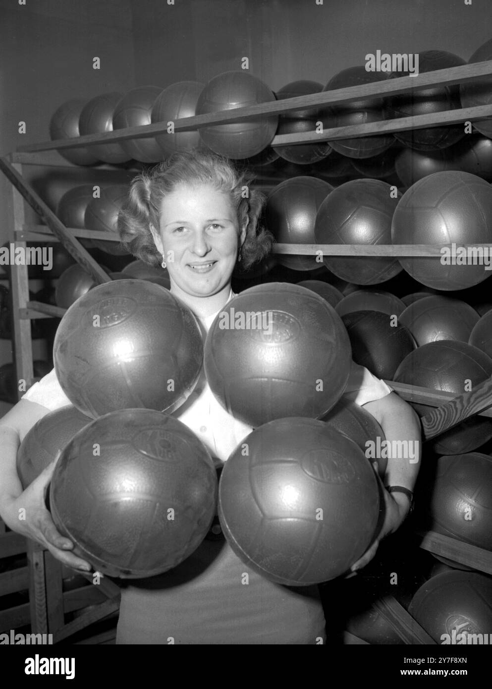 Smiling West Berlin factory worker carries an armful of plastic ...