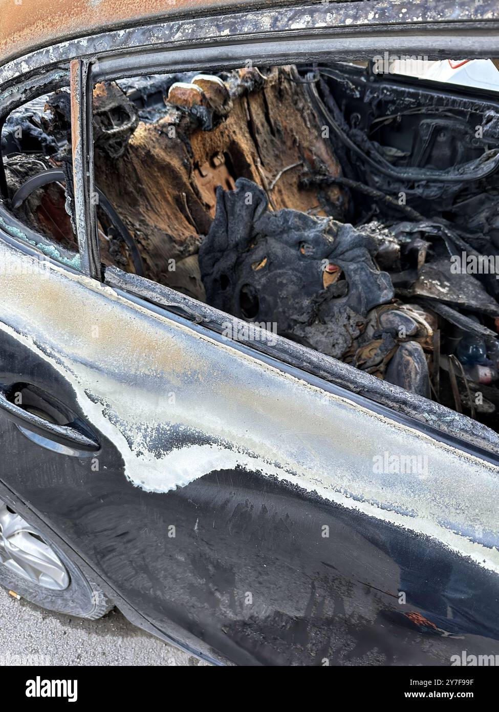 A close-up of the interior of a burnt car. The seats, dashboard, and ...