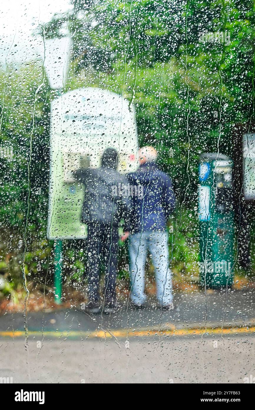 Back view tourist couple arrived at car park standing in rain at ...