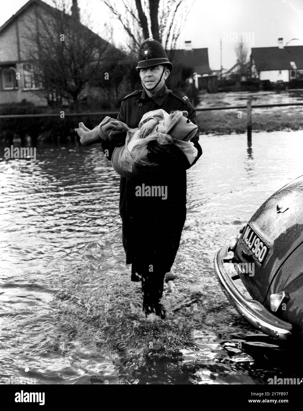 A policeman carries a baby through the flood at Canvey Island, Essex ...