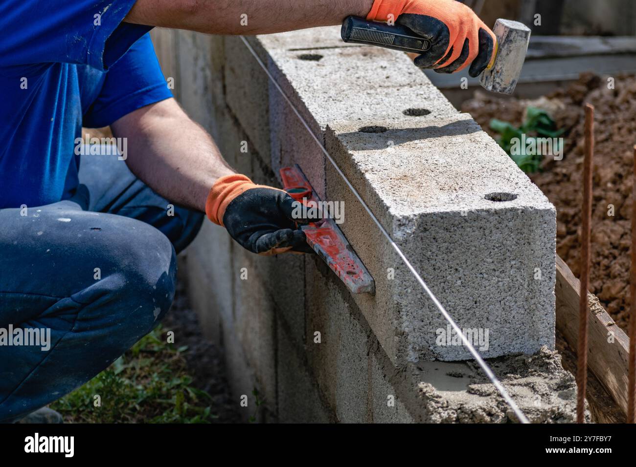 A bricklayer works on blocks to build a wall on a construction site ...