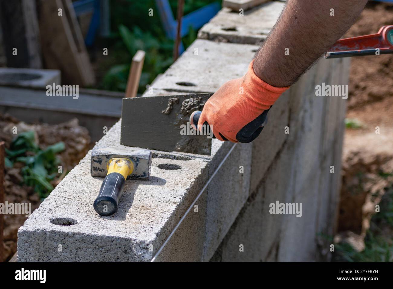 A bricklayer works on blocks to build a wall on a construction site ...