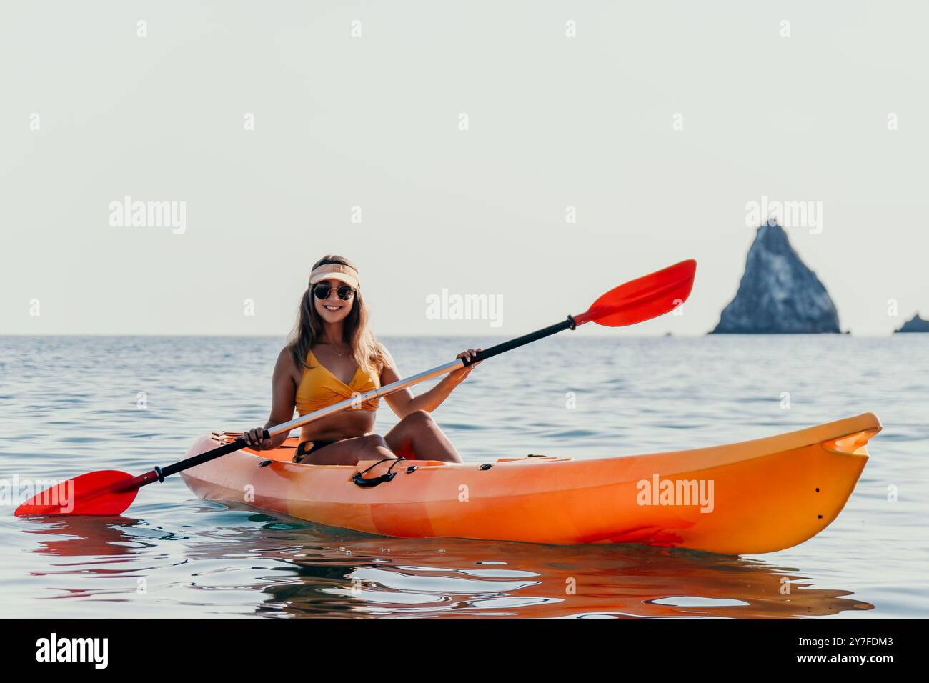 Woman Kayaking Ocean Beach Sunset - A woman in a bikini paddles a kayak ...