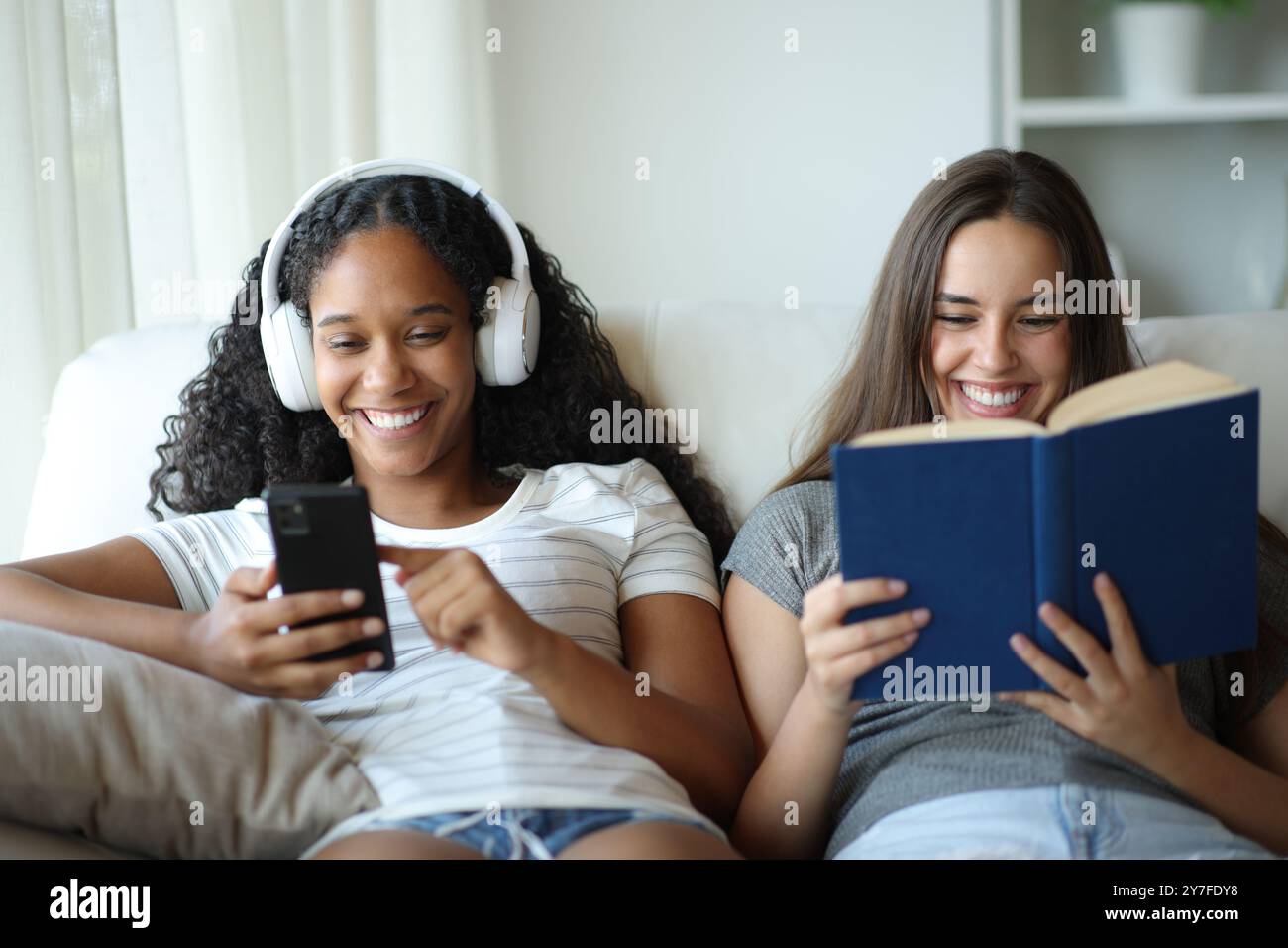 Happy couple enjoying different hobbies sitting on a couch at home ...