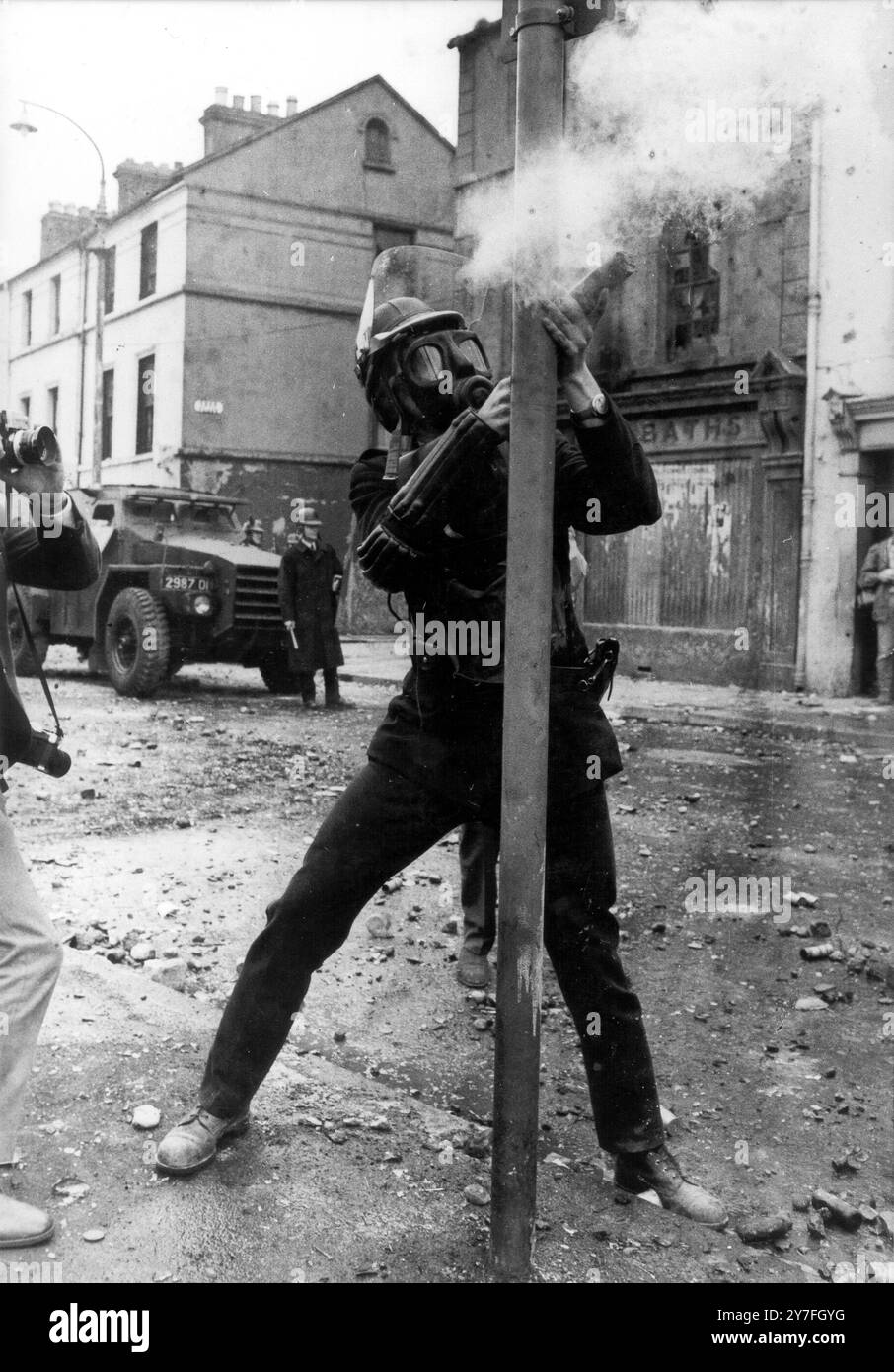 A RUC police officer fires a tear gas pistol at rioters on top of a ...