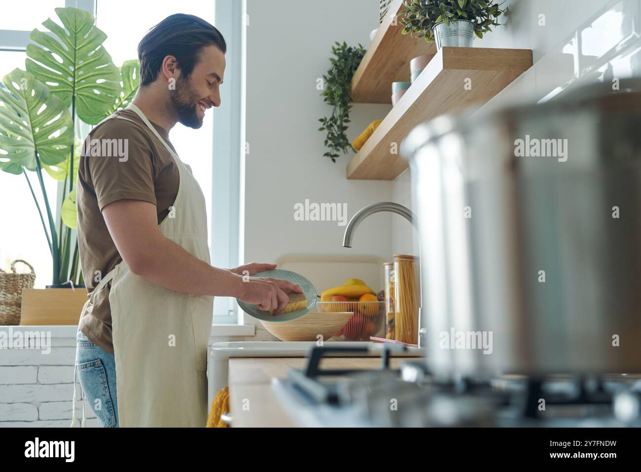 Handsome young man washing dishes at the domestic kitchen Stock Photo ...
