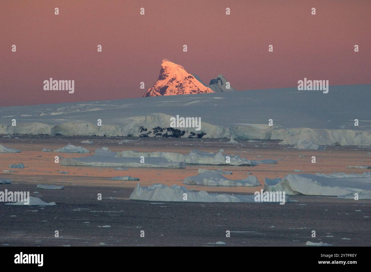 The pink sunset casts its glow on the a peak of the Fish islands in the ...
