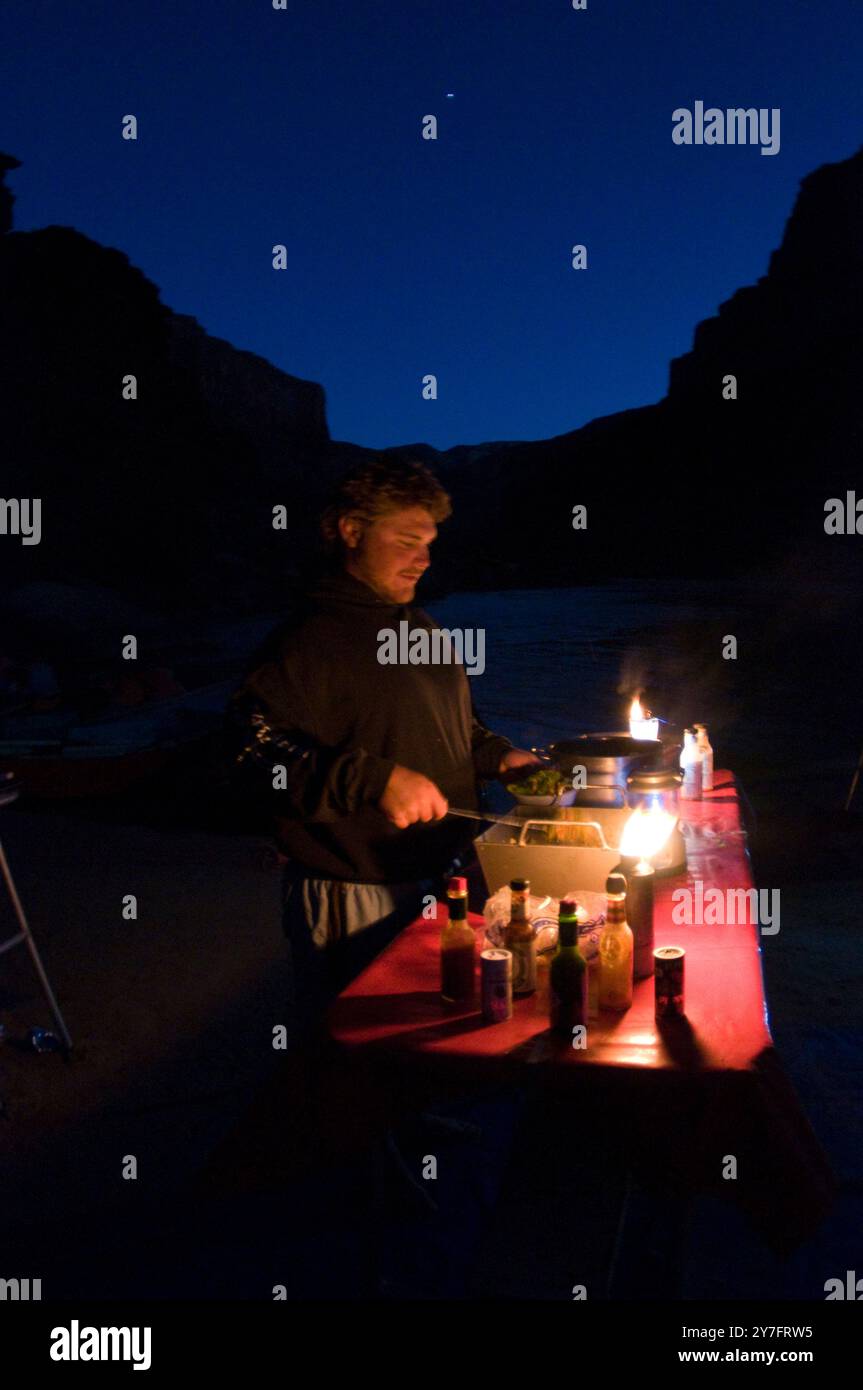 A man prepares dinner at night by the side of the Colorado River Stock ...