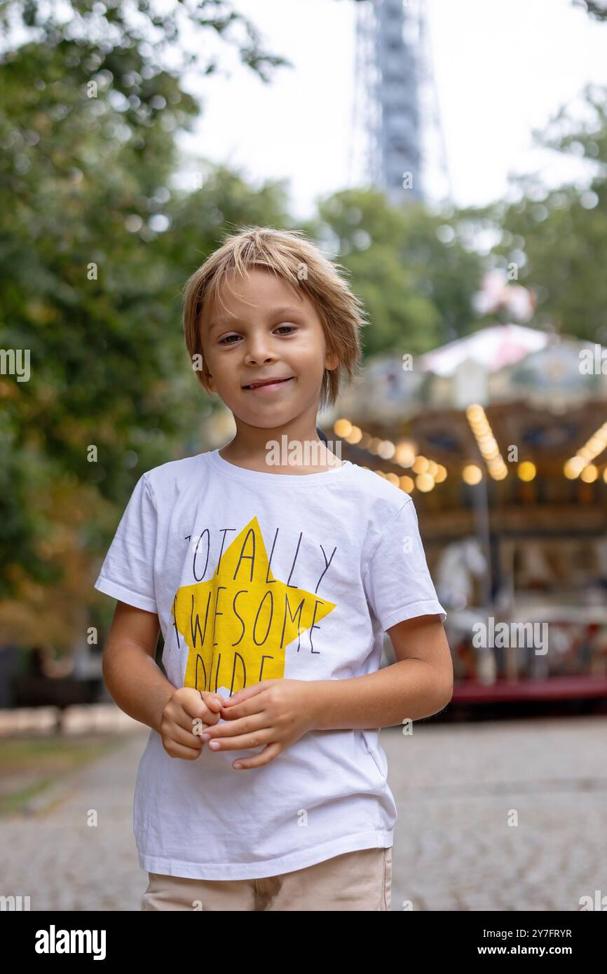 Cute blond child, going on Merry Go Round, kid play on carousel park ...