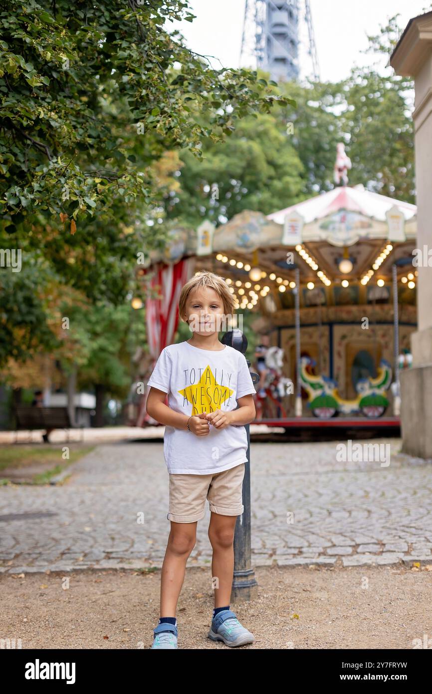 Cute blond child, going on Merry Go Round, kid play on carousel park ...