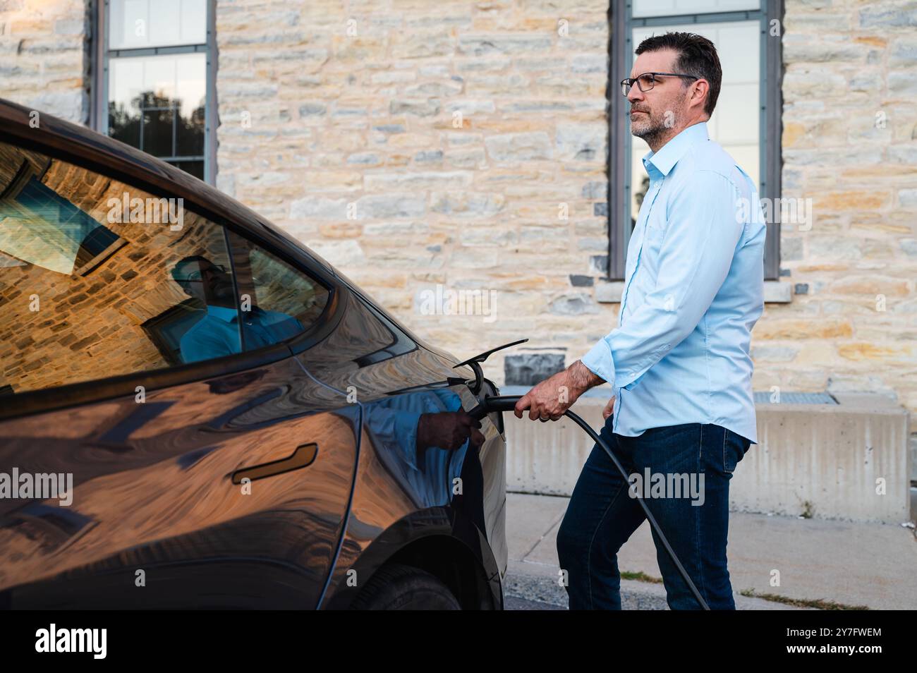 Man using EV charger for electric vehicle at charging station Stock ...