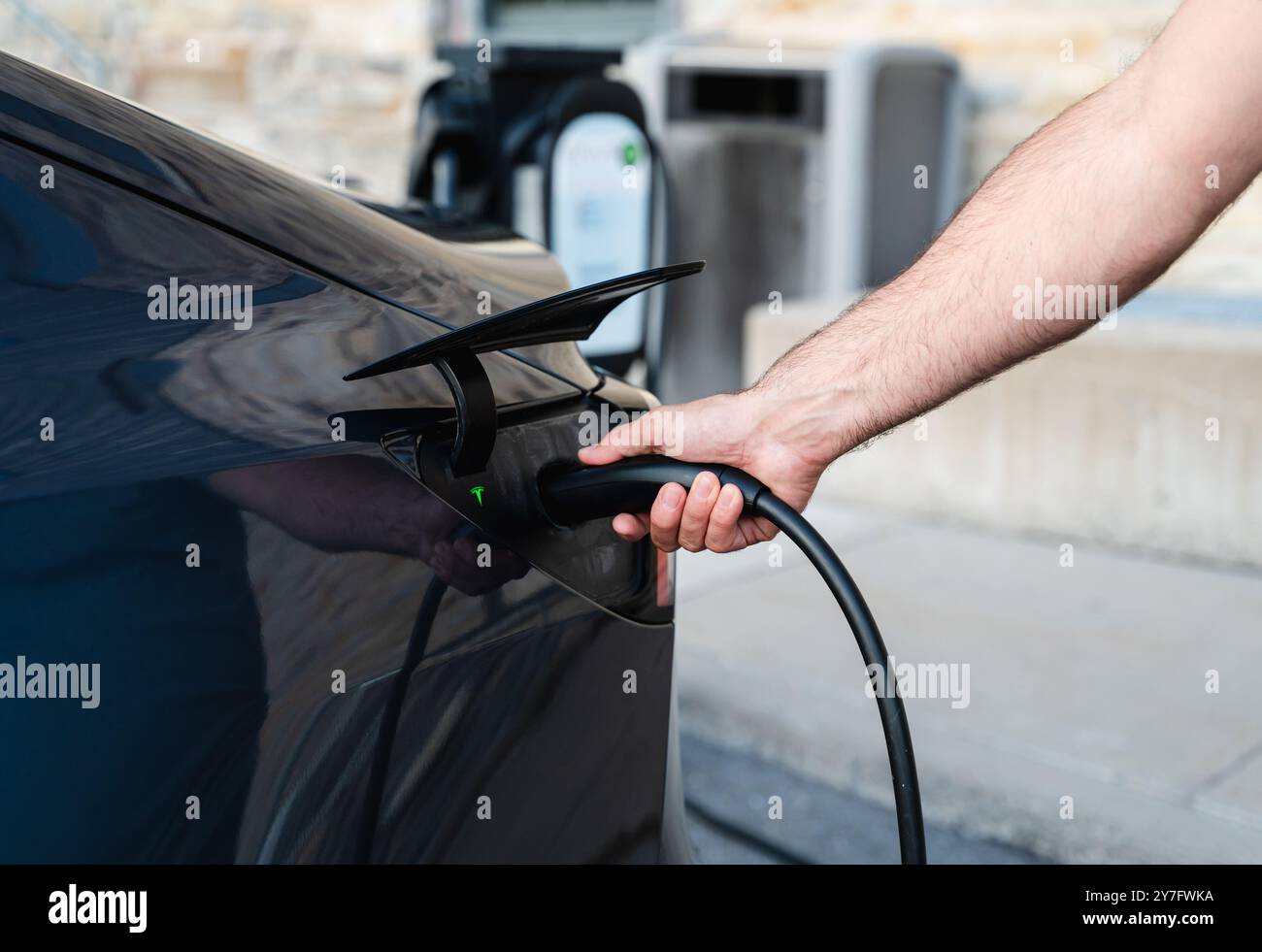 Close up of arm plugging EV charger into electric vehicle outside Stock ...