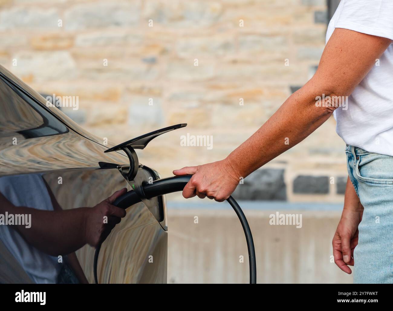 Close up of arm plugging EV charger into electric vehicle outside Stock ...