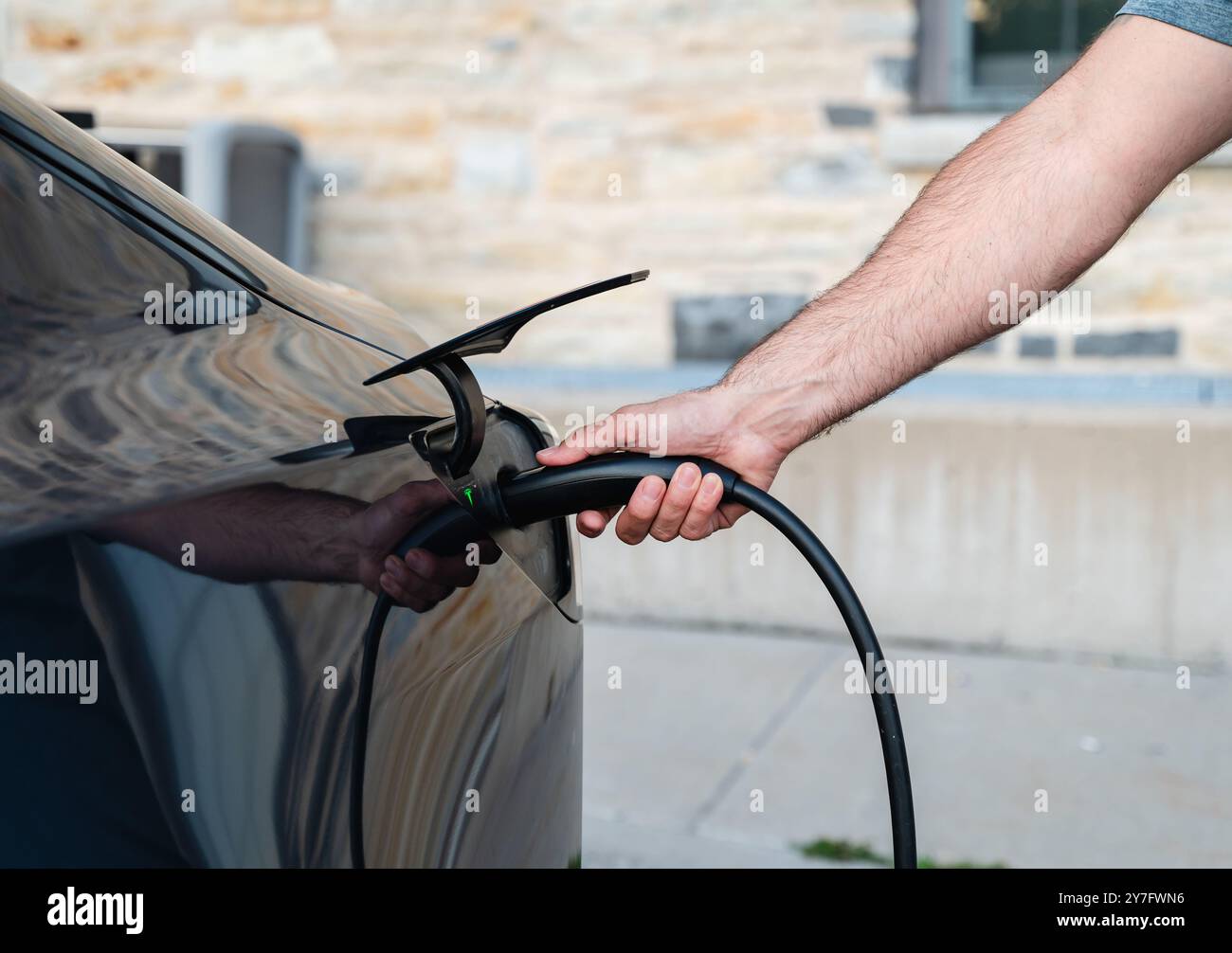 Close up of arm plugging EV charger into electric vehicle outside Stock ...