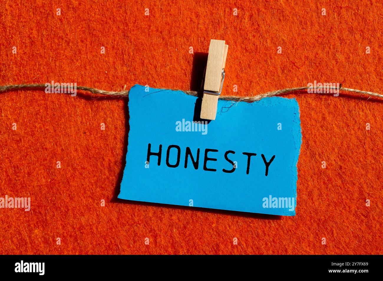 Honesty message written on ripped blue torn paper piece on orange ...