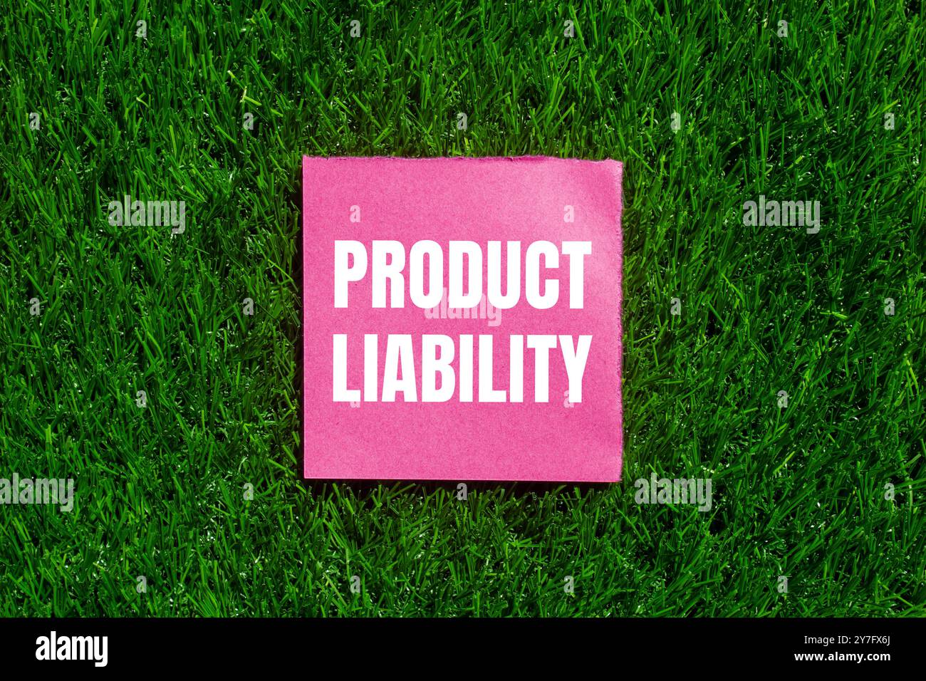 Product liability message written on ripped torn pink paper with green ...
