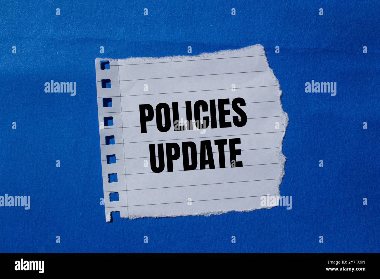 Policies update message written on ripped torn paper piece with blue background. Conceptual ...
