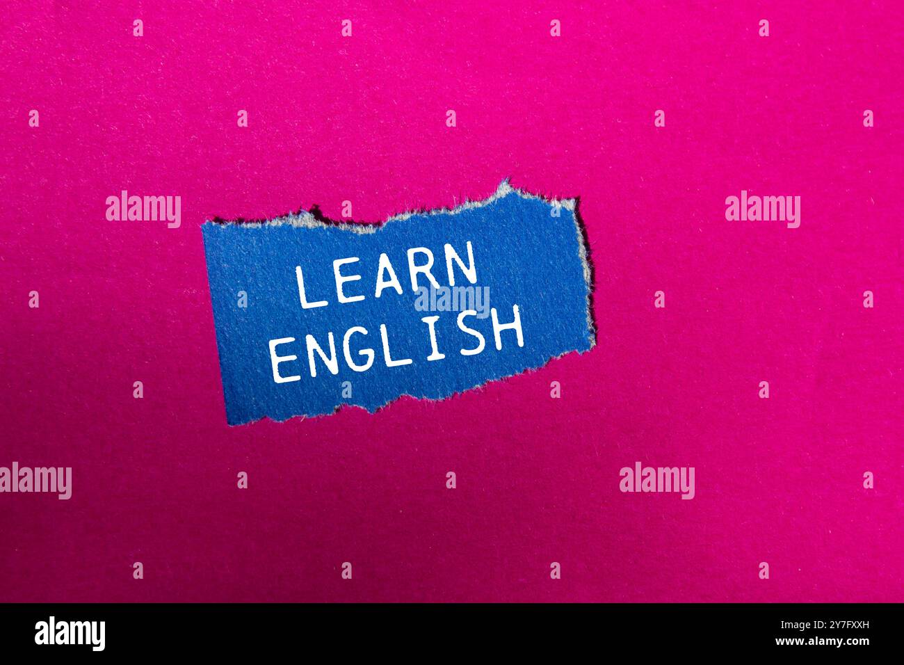 Learn english message written on ripped blue torn paper piece on pink background. Conceptual ...
