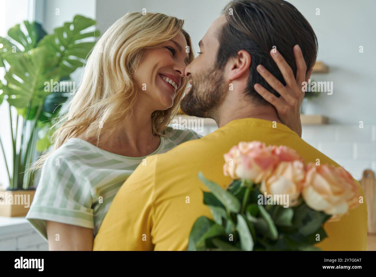 Handsome young man surprises his girlfriend with bunch of flowers at ...