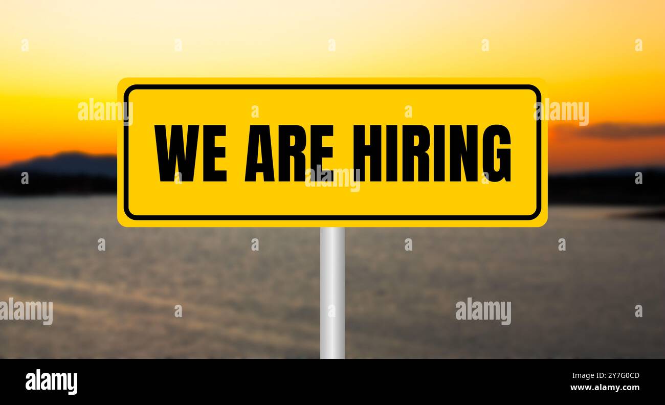 We are hiring message written on yellow sign with blurry lake ...